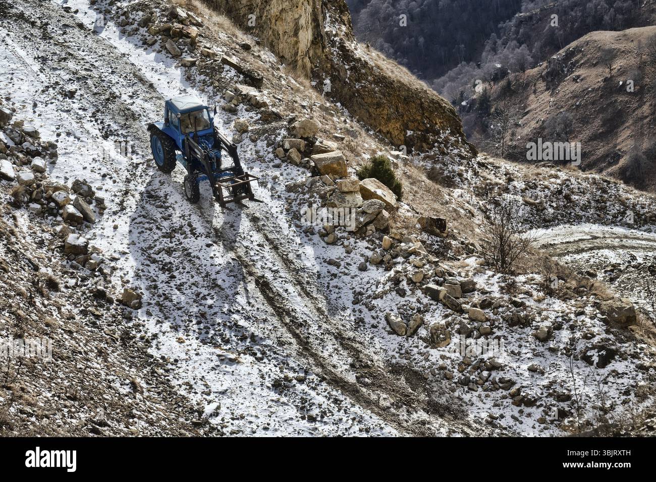 Tractor with hay loader down mountain country road in winter ...