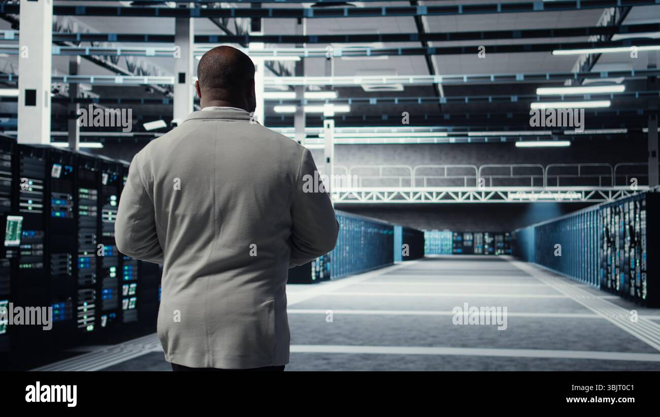 Technician walking in data center workplace with multiple rows of fully ...