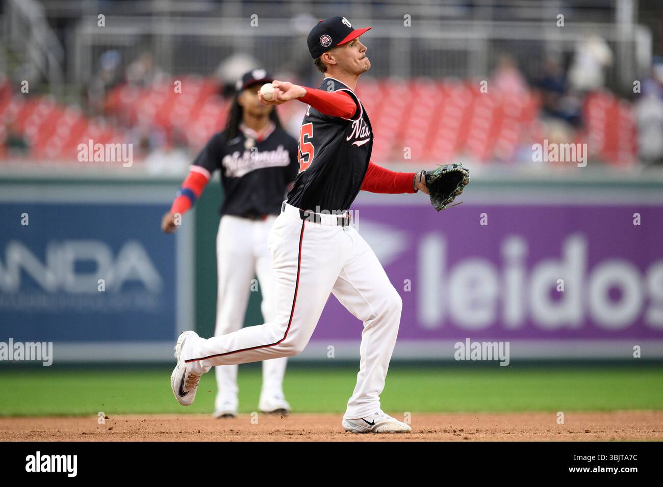 Washington Nationals third baseman Brady House, foreground, throws to ...