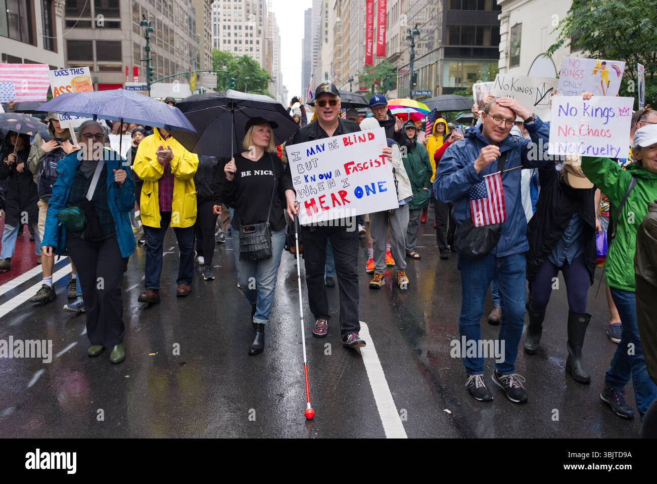 A protest march on a rainy city street. Participants hold signs with ...