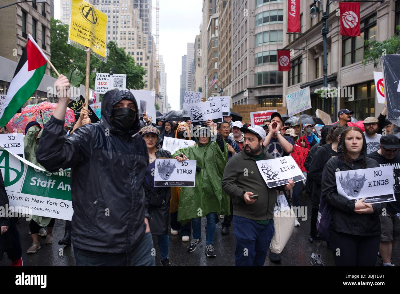 A protest march in a city street during rain. Many protesters carry ...