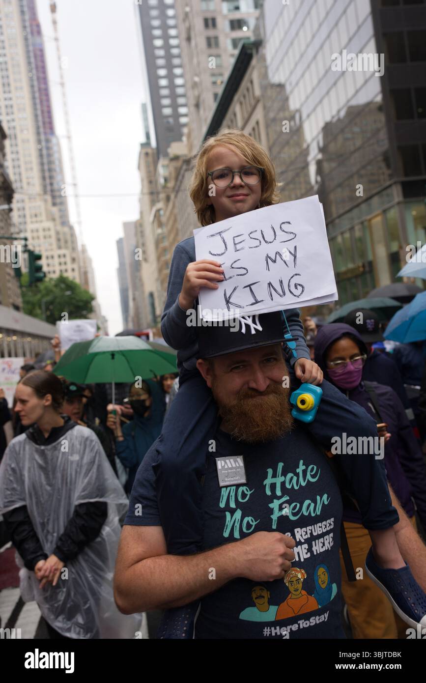 A man carries a child on his shoulders at a protest. The child holds a ...