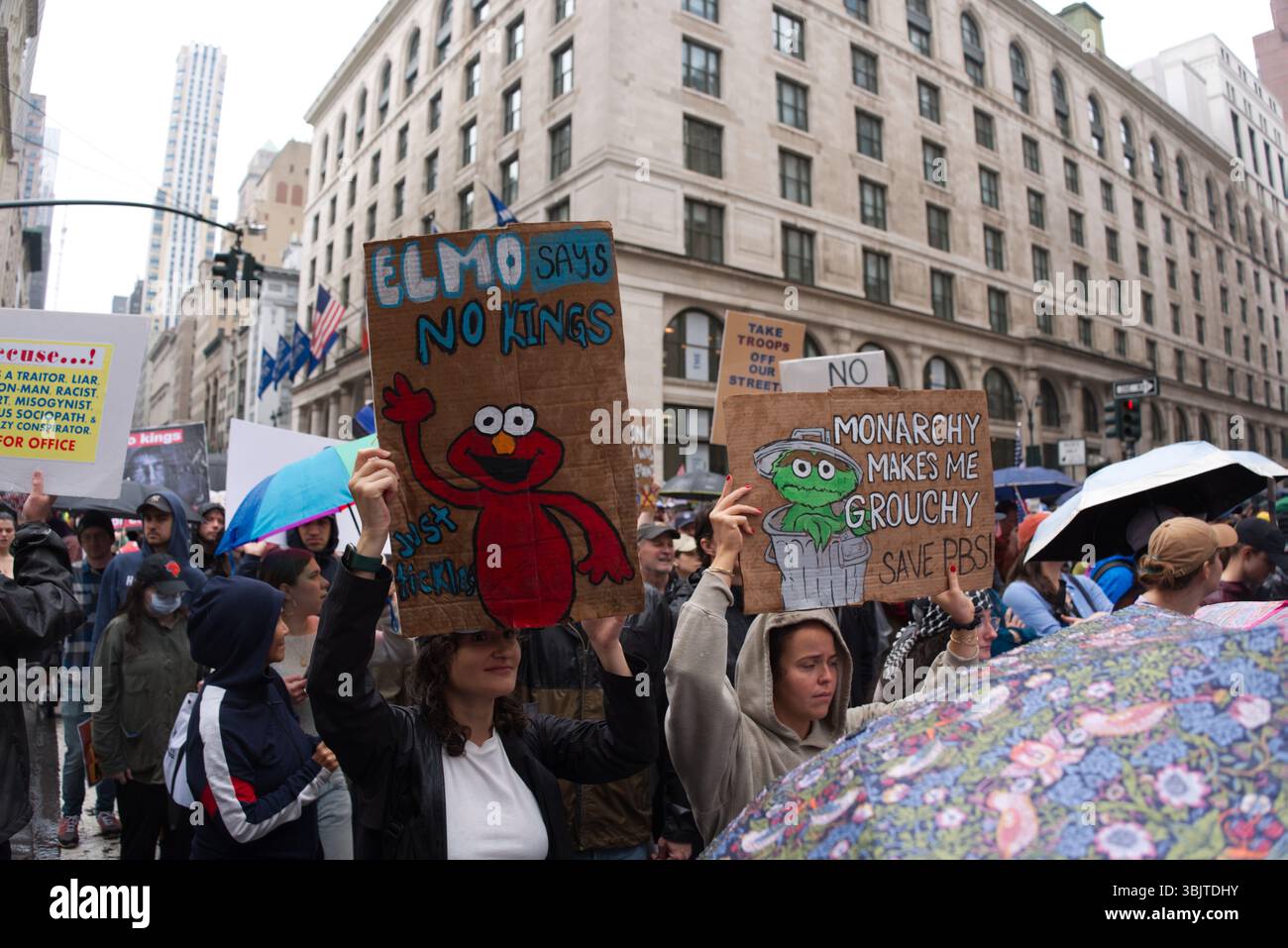 A protest in a city setting features people holding signs with hand ...