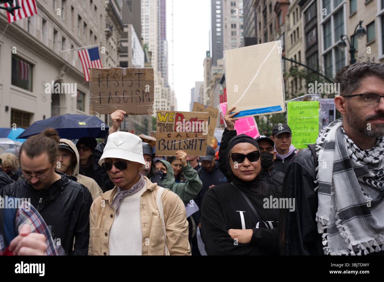 A diverse crowd of protestors march down a city street, holding signs ...