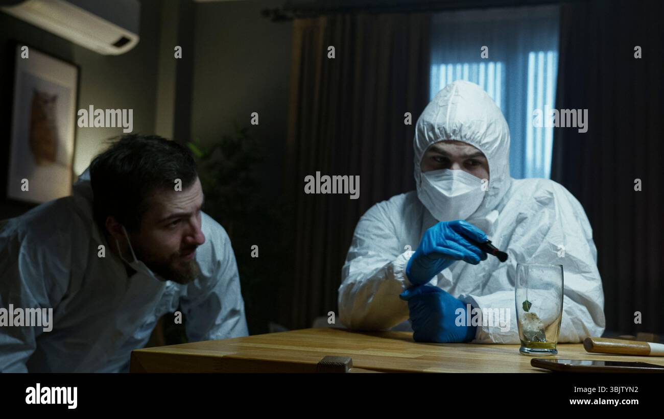 Forensic investigator in a white hazmat suit and blue gloves closely ...