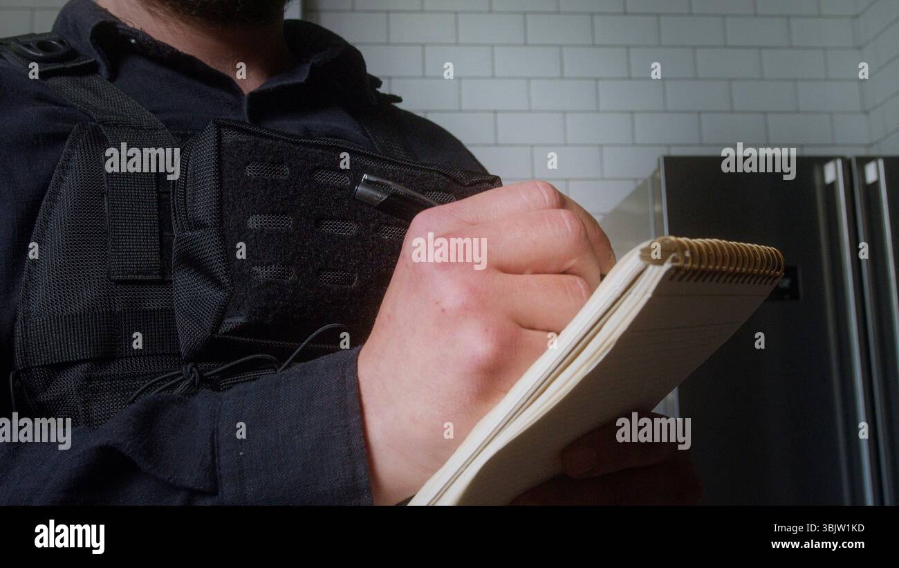 Closeup of a uniformed police officer writing in a notepad, possibly ...