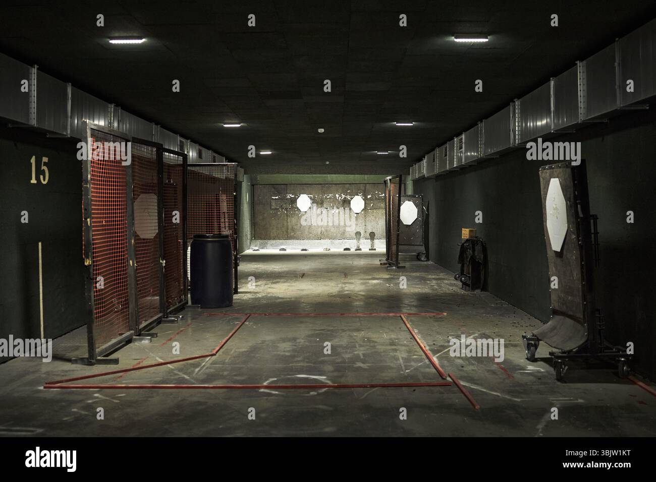 Empty indoor shooting range featuring multiple paper targets on ...