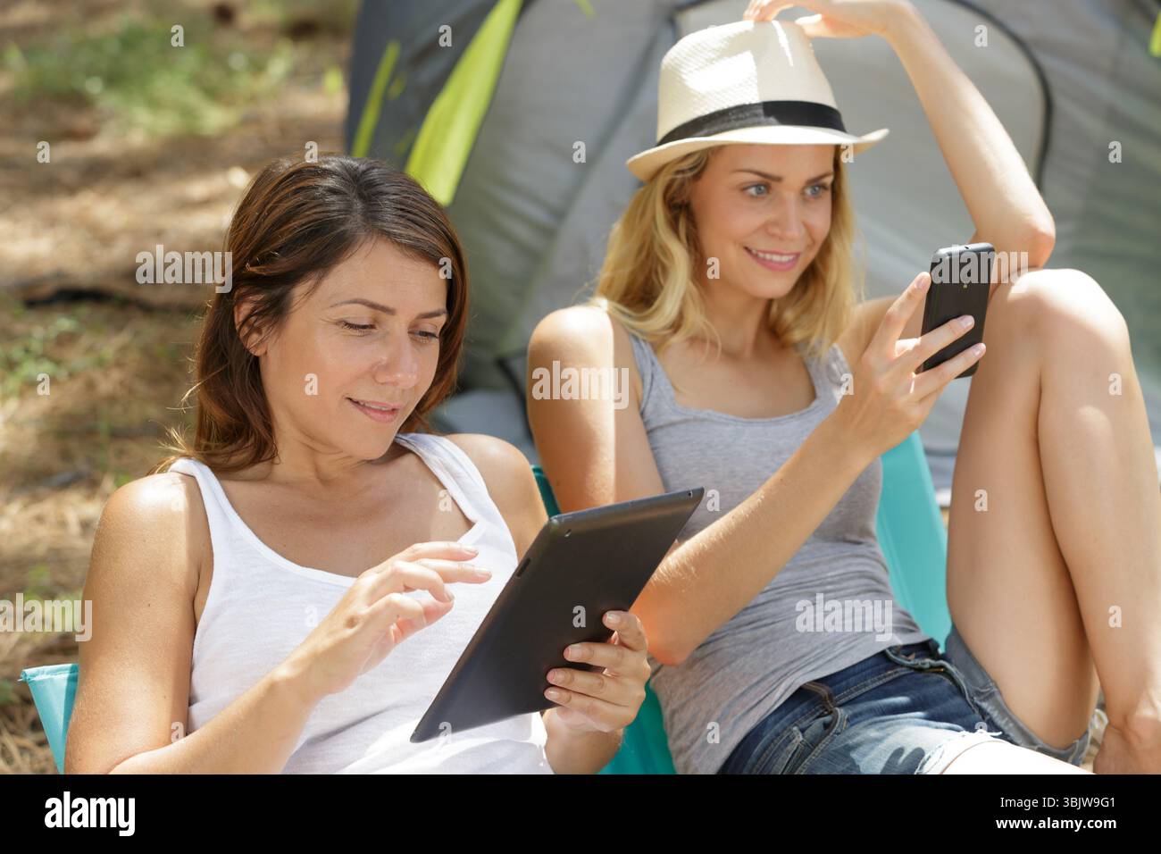 camping girls using smartphone and tablet Stock Photo - Alamy
