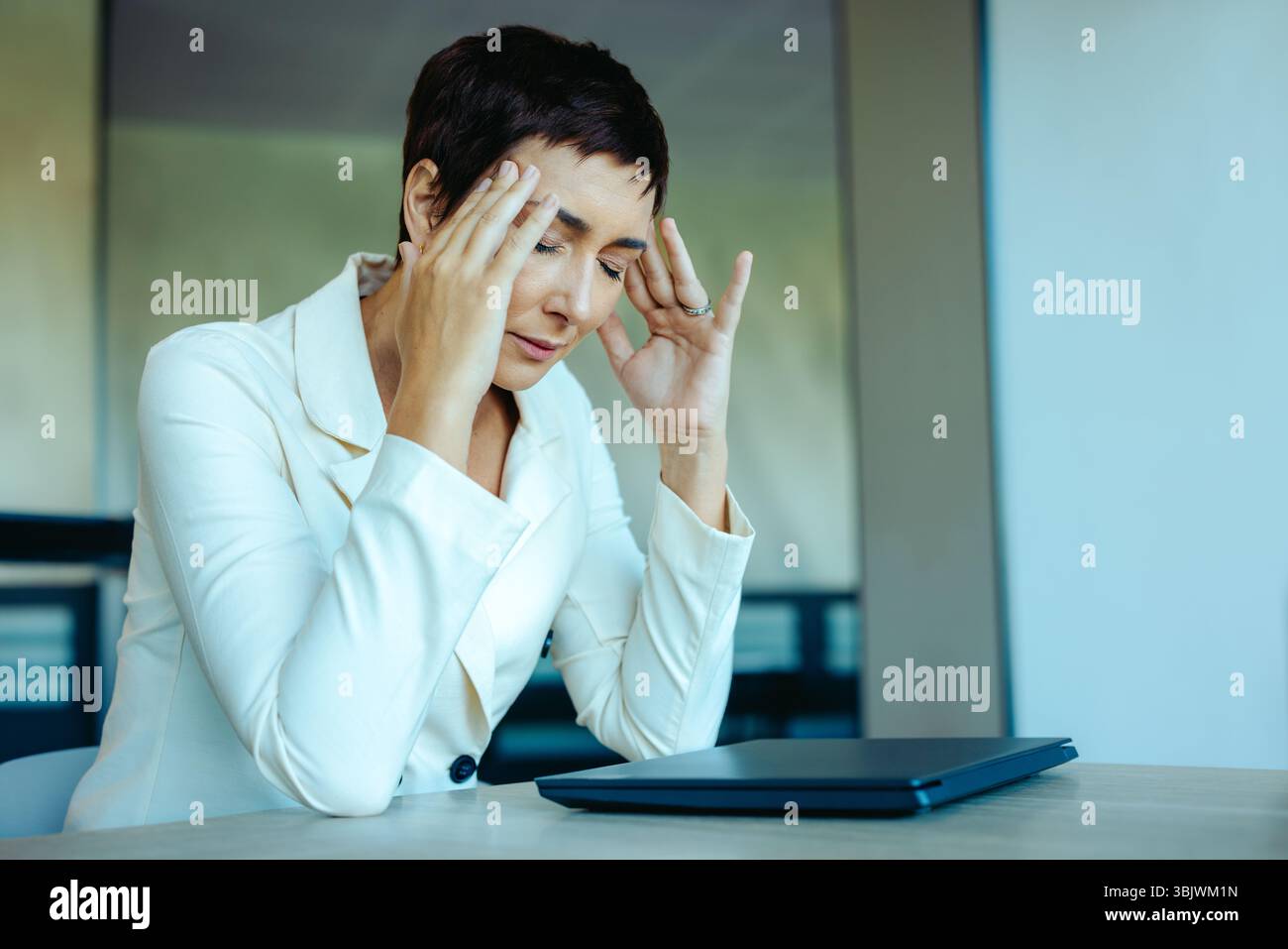 A businesswoman in an office setting looks overwhelmed, with her hands ...