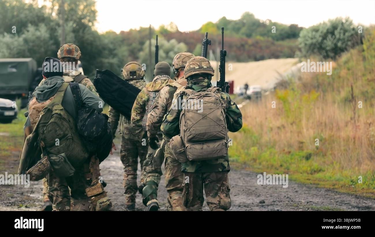 Soldiers walking in the field, armed and equipped. A group of soldiers ...