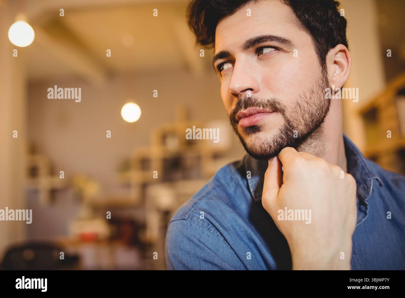Man is sitting at desk in café workspace under hanging light bulbs and ...