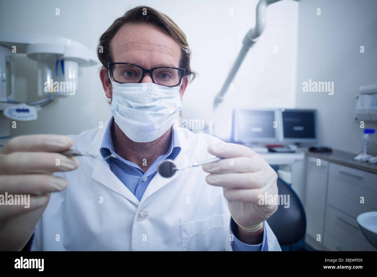Dental mirror and explorer probe pointing toward viewer in clinic room ...
