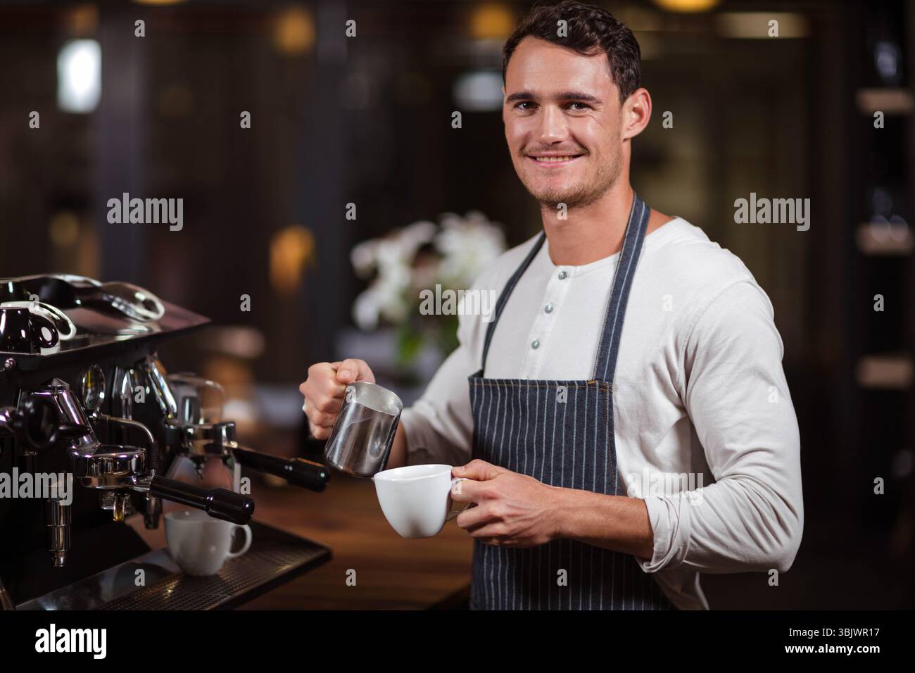 Espresso machine steaming milk in pitcher over coffee cup on wooden ...