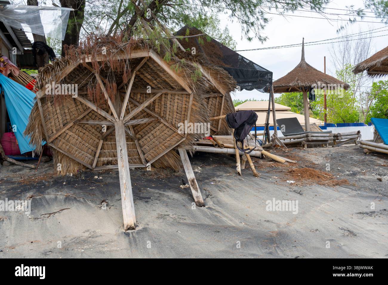 Hut with a broken roof sits on a beach. The hut is surrounded by a tarp ...