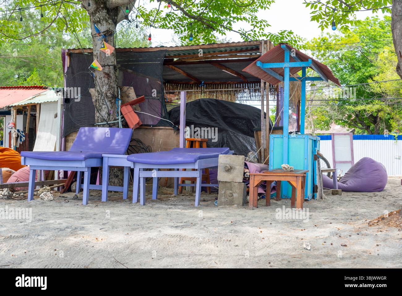 Beach hut with a blue roof and a purple bench. The hut is empty and has ...