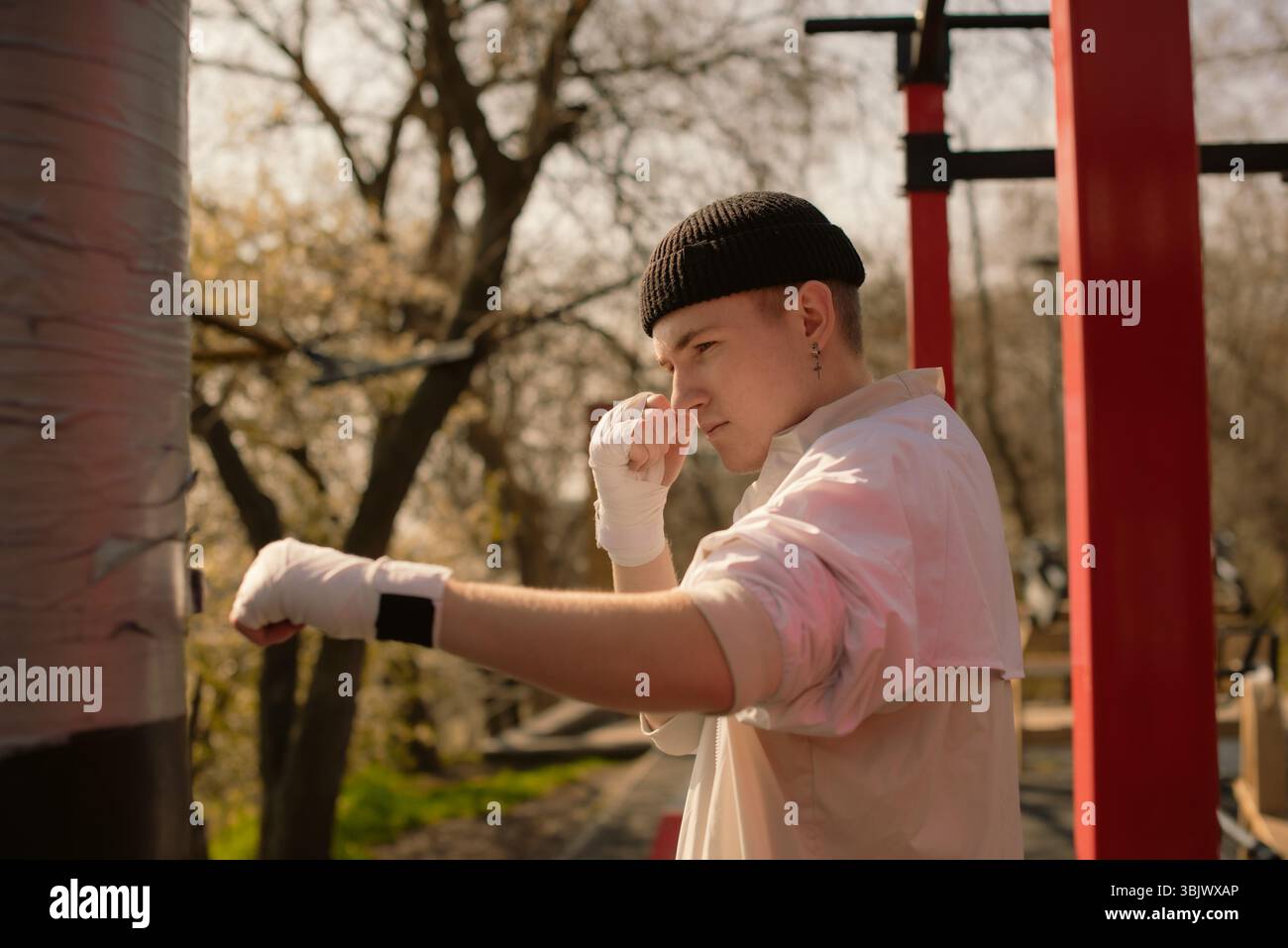 Solo Boxing Session: Teen Using Punching Bag Outside Stock Photo - Alamy