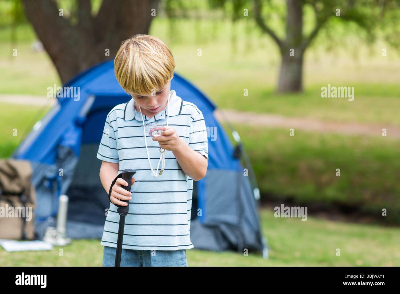 Blue tent standing in grassy clearing with compass on trekking pole by ...