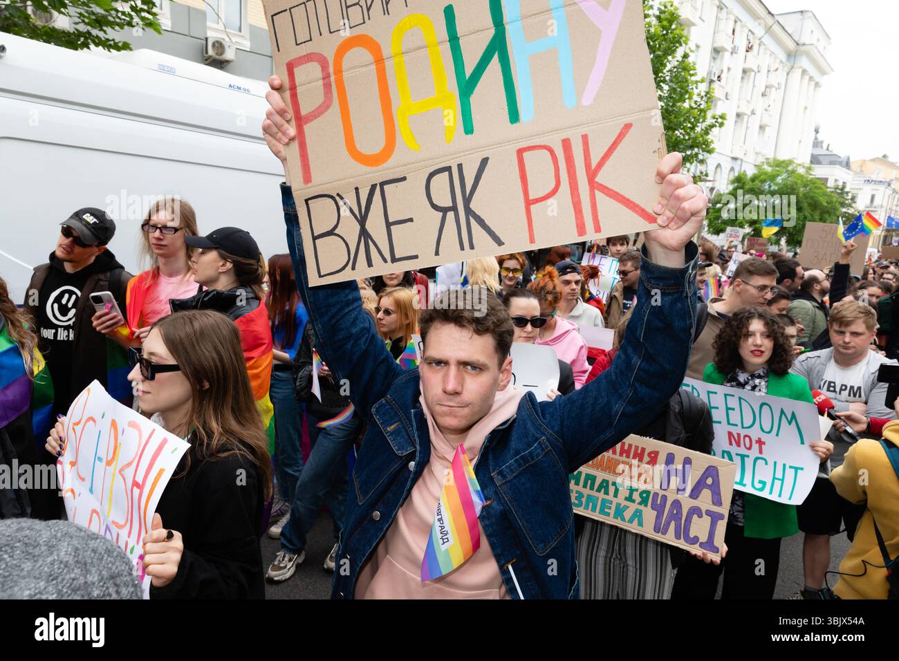 A group of people march in a pride parade holding placards with ...