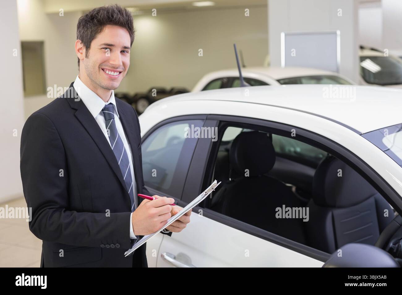 Man standing holding clipboard and red pen in showroom near white ...