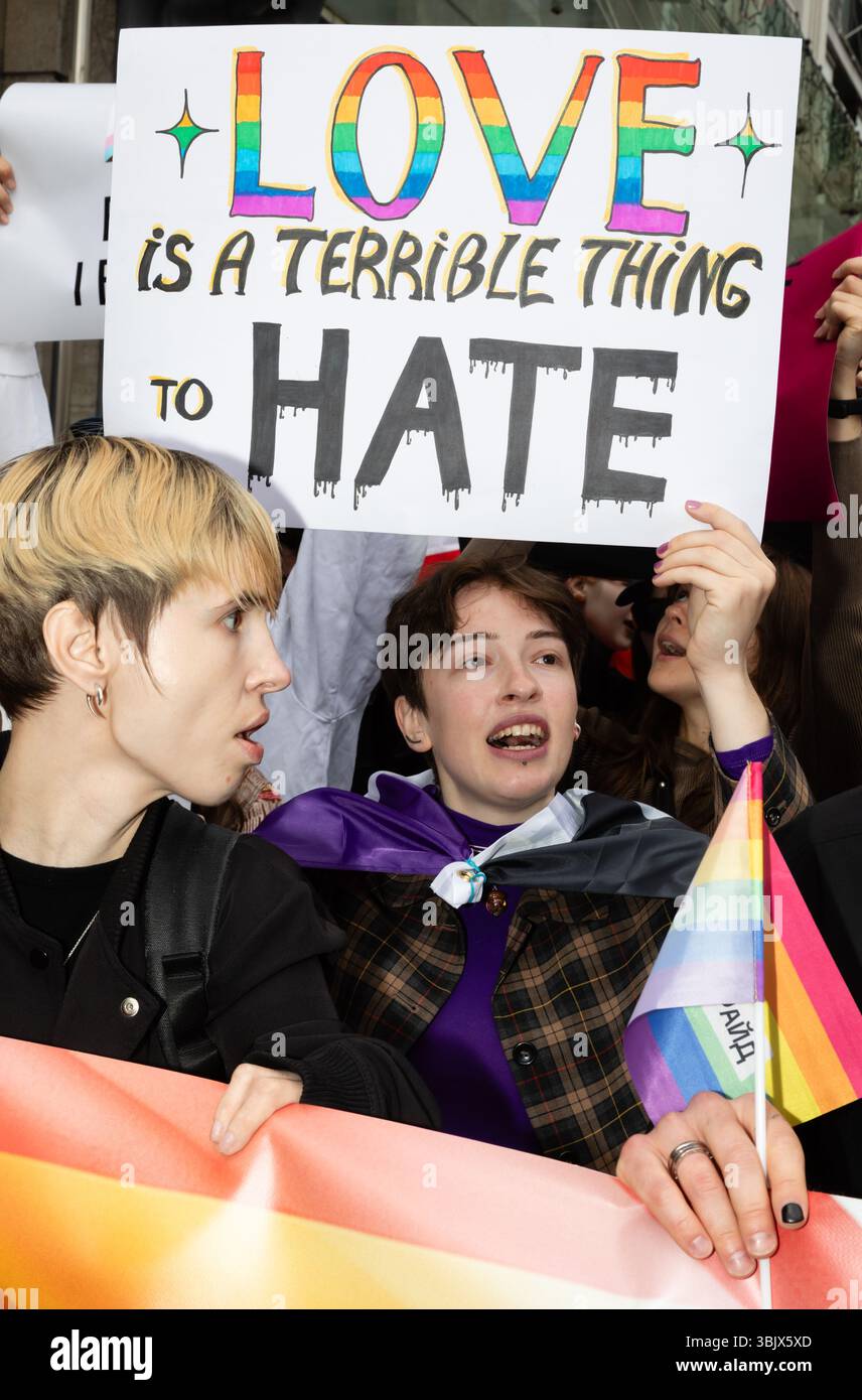 People at a pride parade hold signs and flags celebrating love and ...