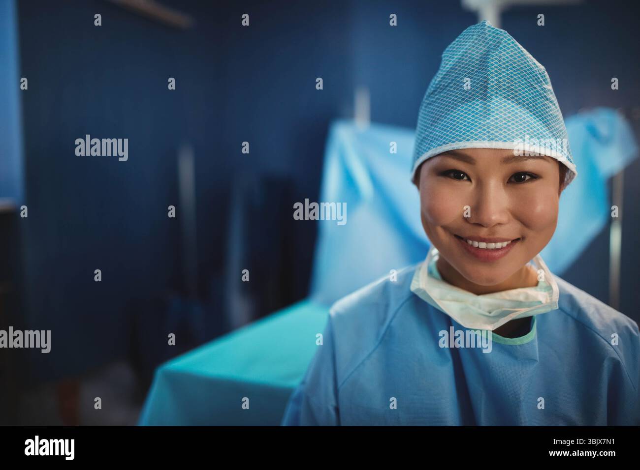 Asian female surgeon standing right of draped table in operating room ...