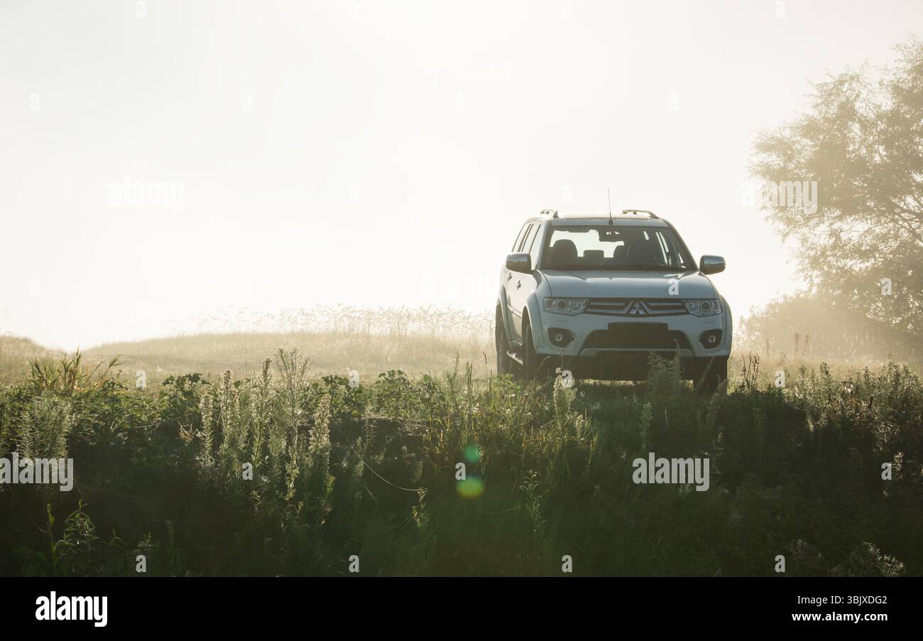 Mitsubishi Pajero Sport in a meadow in morning fog. White SUV at ...
