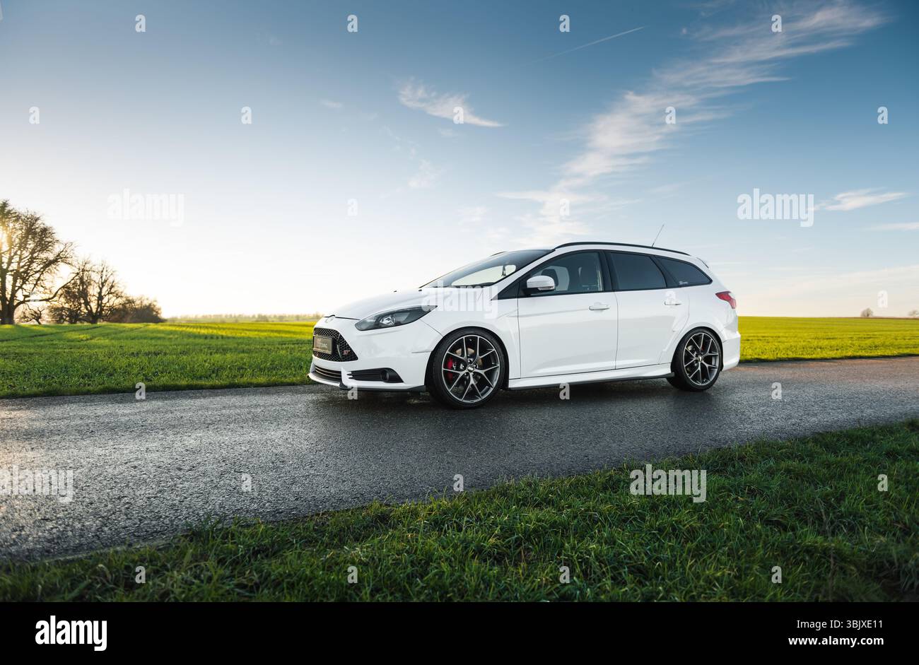White Ford wagon on a rural road. Side view of Ford Focus car on narrow ...