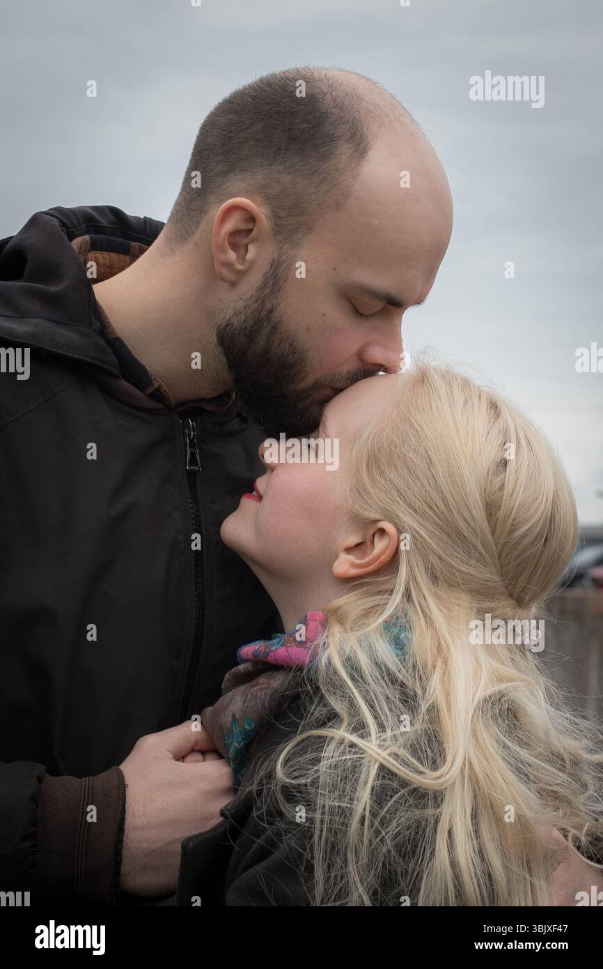 Cheerful young woman with long blonde hair and man couple hugging each ...