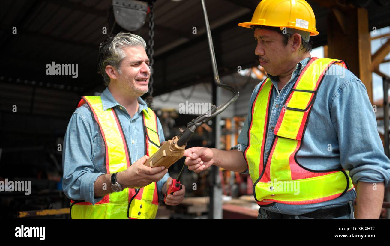 Two workers on a construction site are demonstrating the operation of a ...