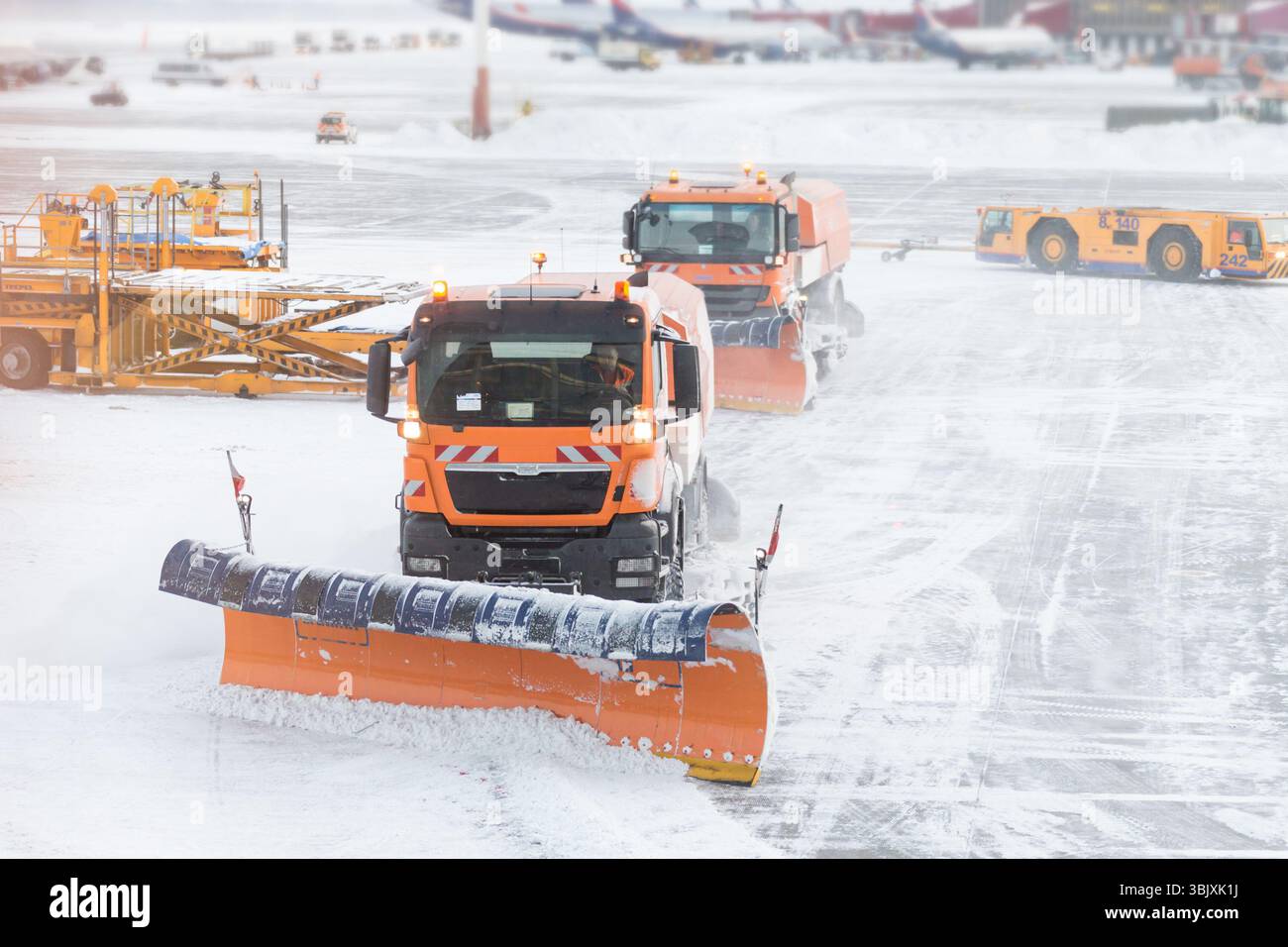 Snowplow removing snow from runways and roads in airport during snow ...