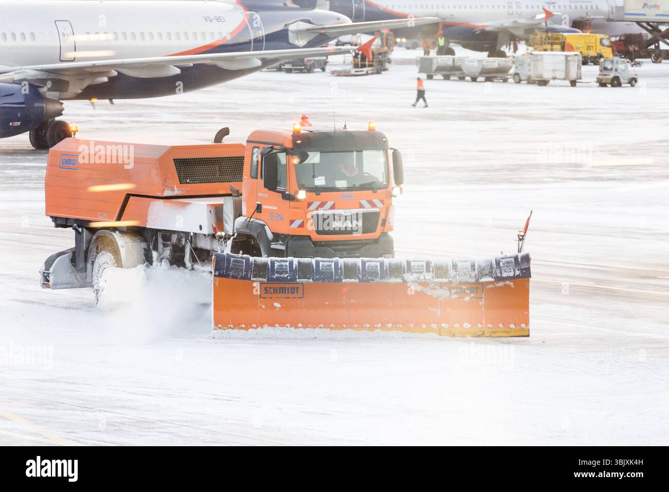 Snowplow removing snow from runways and roads in airport during snow ...