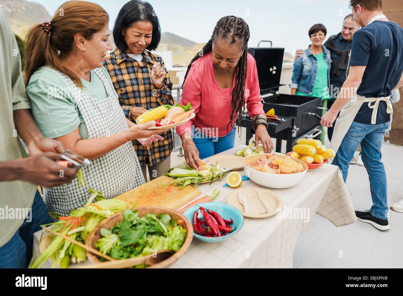 Happy multiracial women preparing food for barbecue at home's rooftop ...