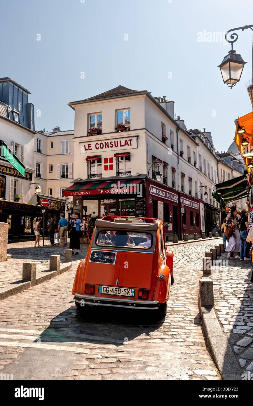 An orange Citroën 2CV driving through Montmartre with in the background ...
