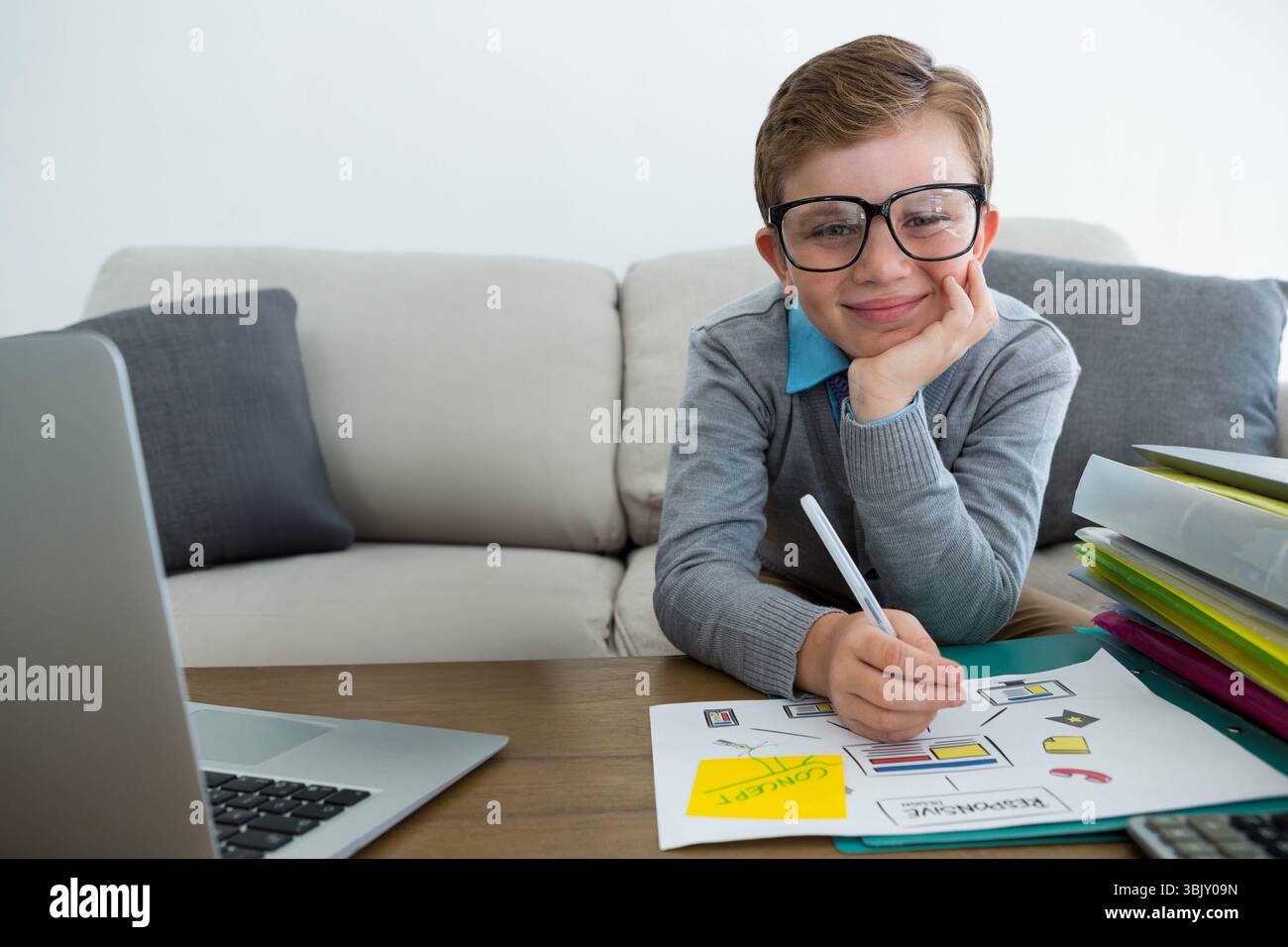 School-age boy drawing diagrams at coffee table in living room with pen ...