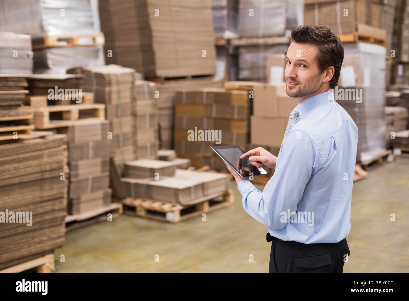 Man in shirt and tie holding tablet while inspecting inventory on ...