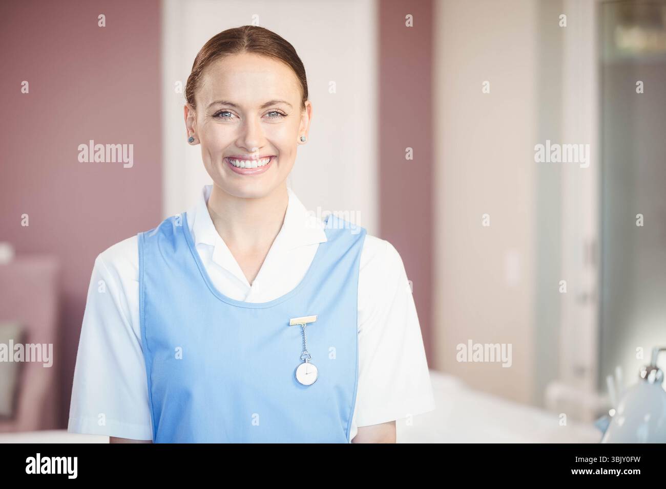 Female nurse smiling near bedside table in hospital room with badge ...