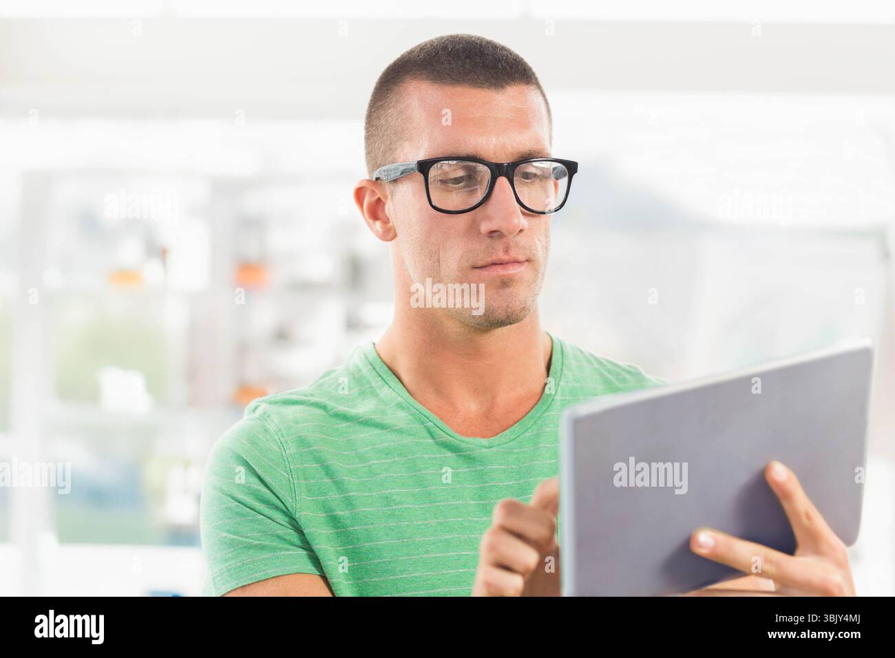 Tapping tablet screen in bright modern office space with white shelving ...