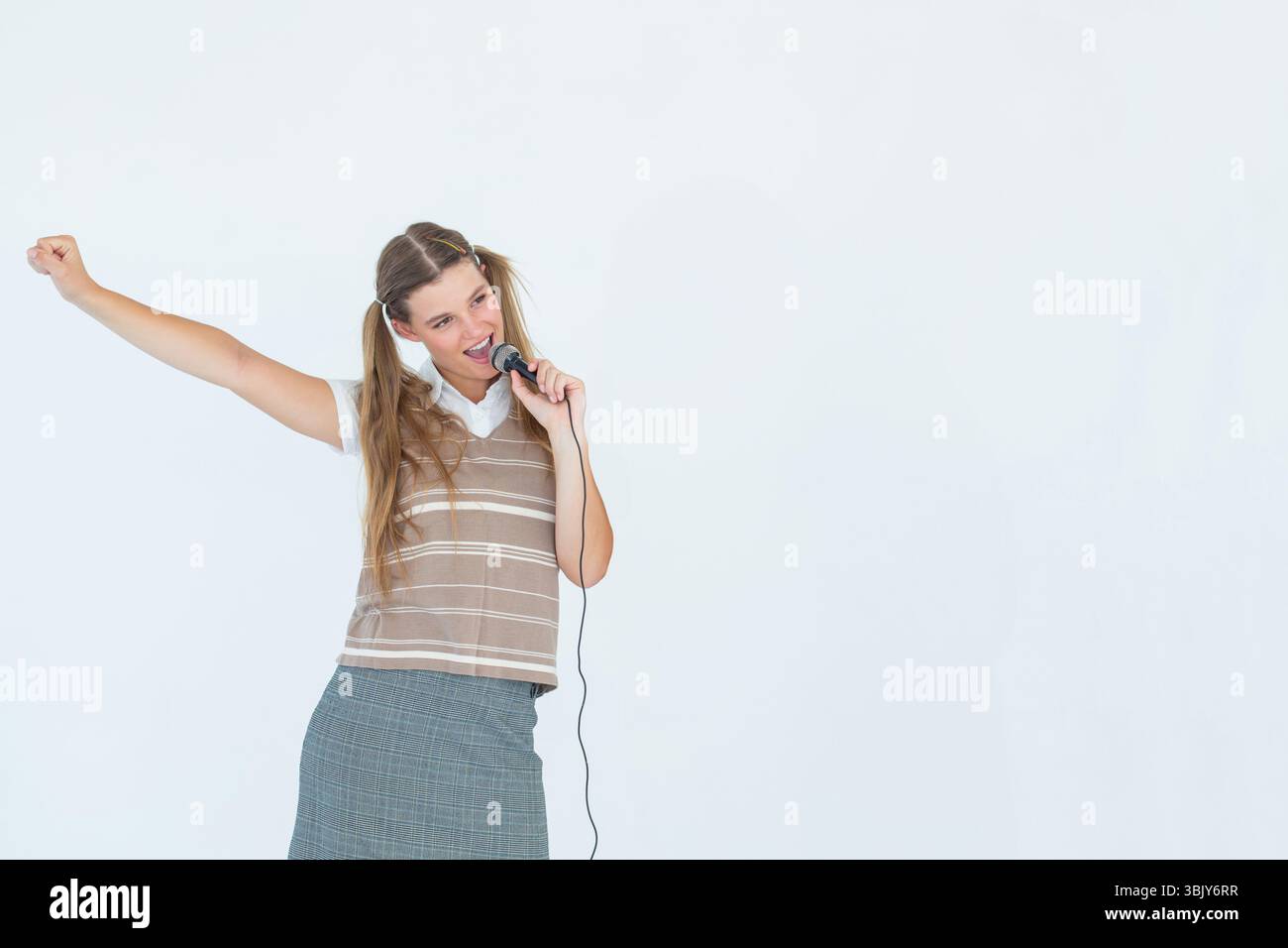 Female performer singing into wired mic in studio wearing striped vest ...