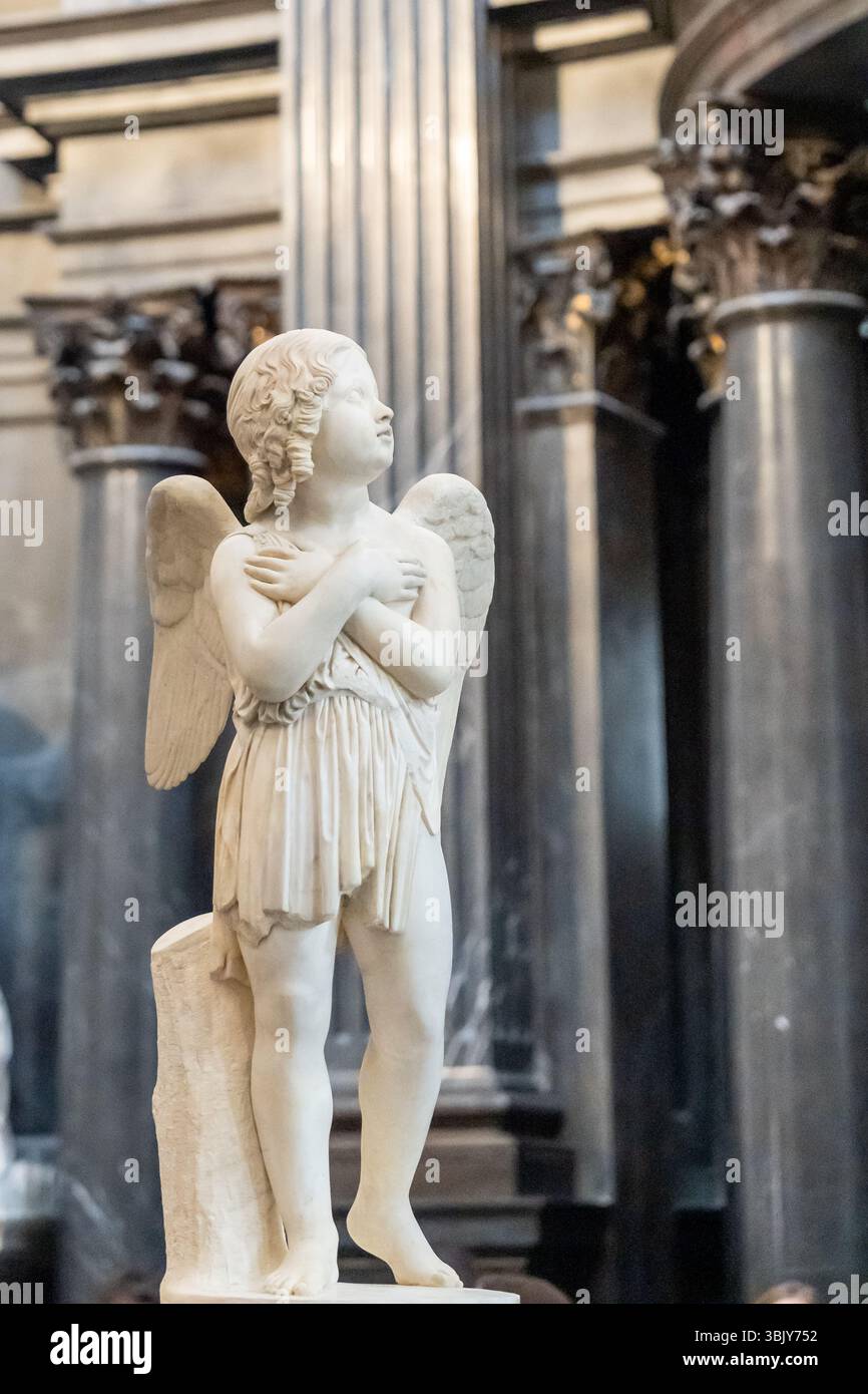Close-up on marble statue of angel boy posing with crossed arms in ...