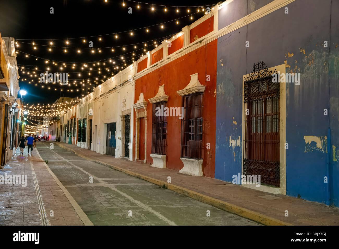 Colored street by night with festive string lights and colonial ...