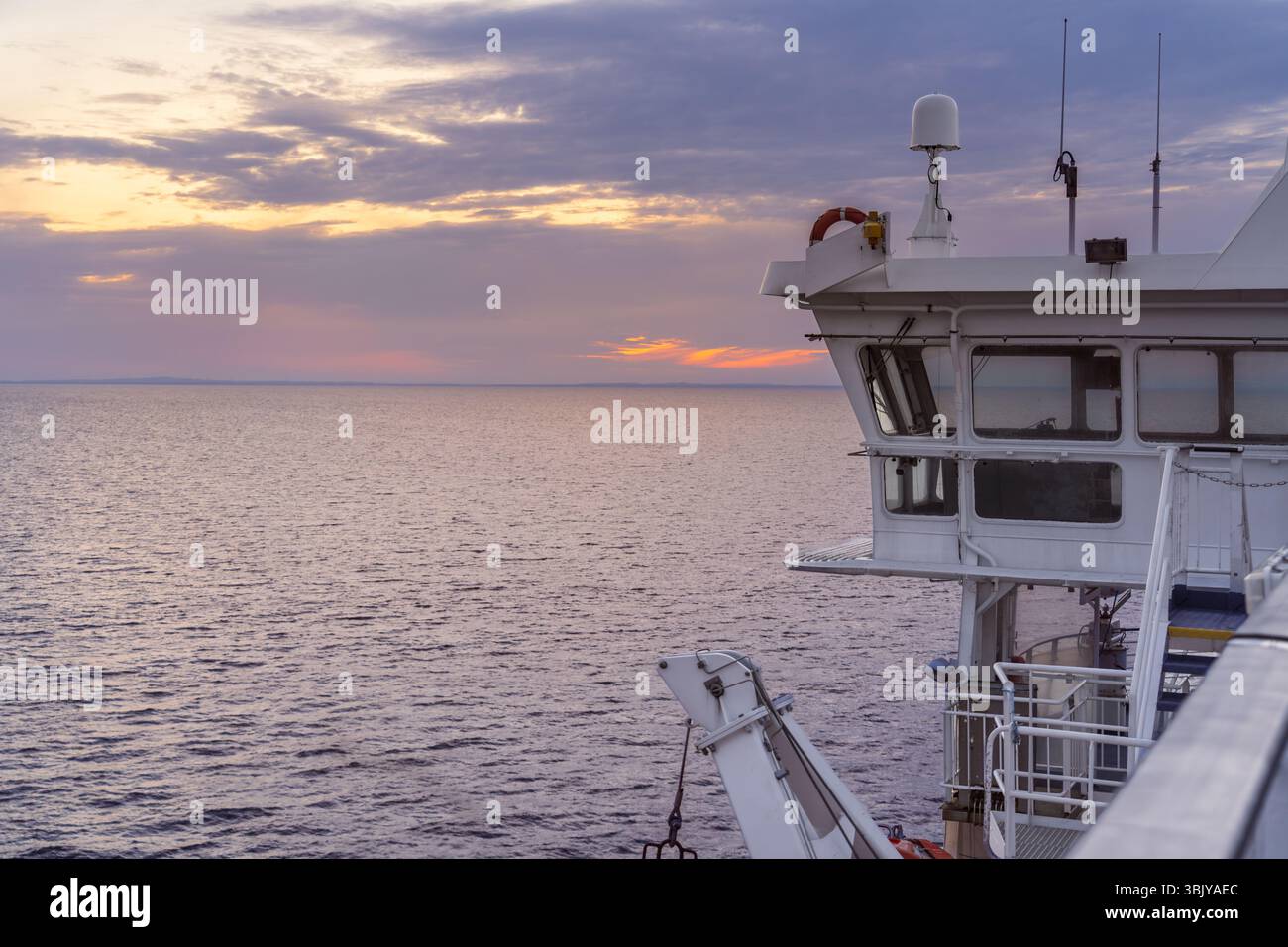 A stunning sunset casts vibrant colors across the sea while the ferry ...