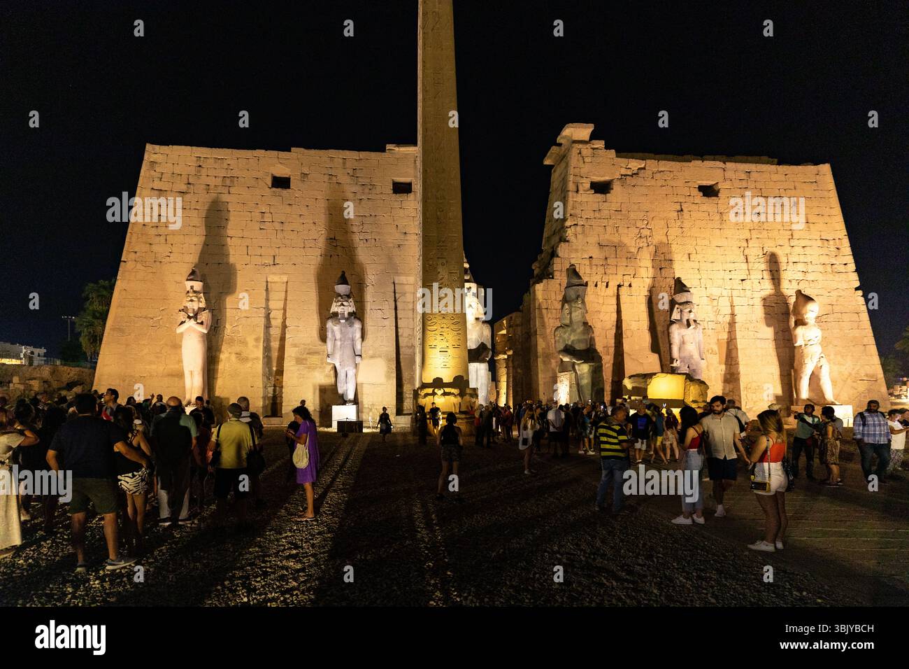 Tourists visit the Luxor Temple in Egypt at night, illuminated by ...