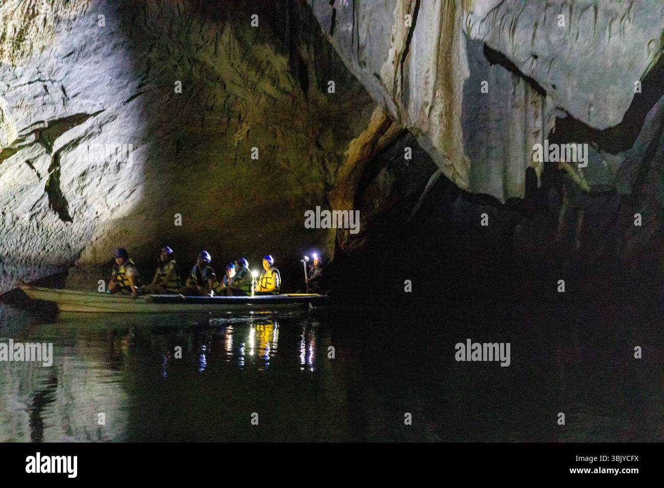 A group of people are on a boat inside a cave, wearing life jackets and ...