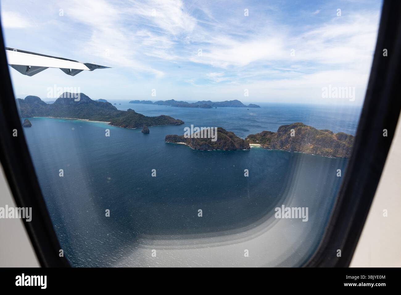 A view from an airplane window shows islands in the ocean, with the ...