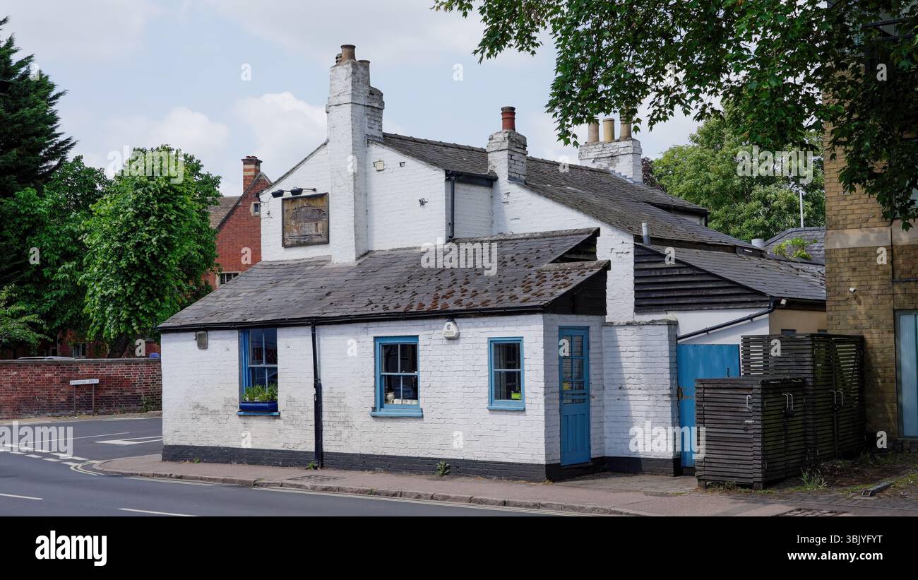 Classic white British pub with blue doors and weathered sign in ...