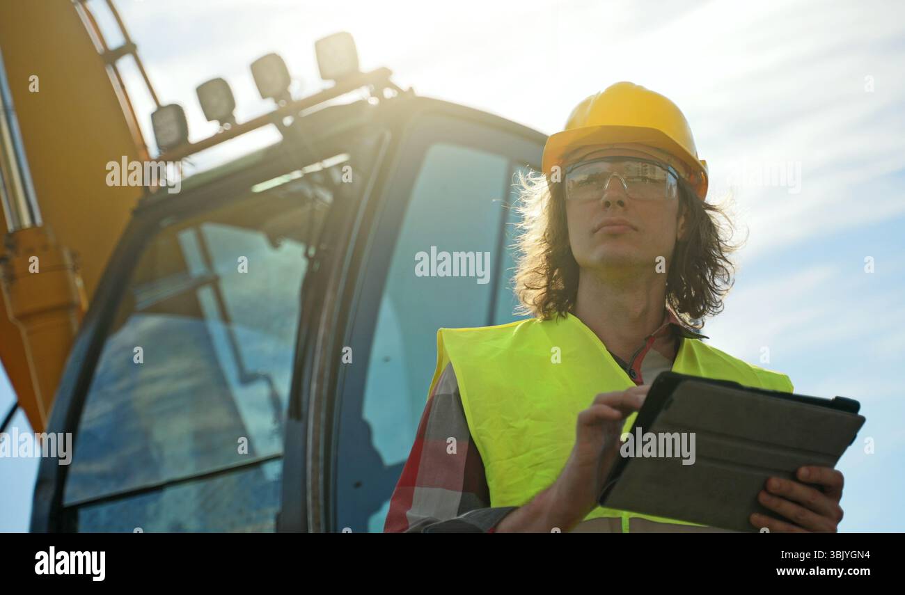 Excavator operator in hard hat using tablet pc Stock Photo - Alamy