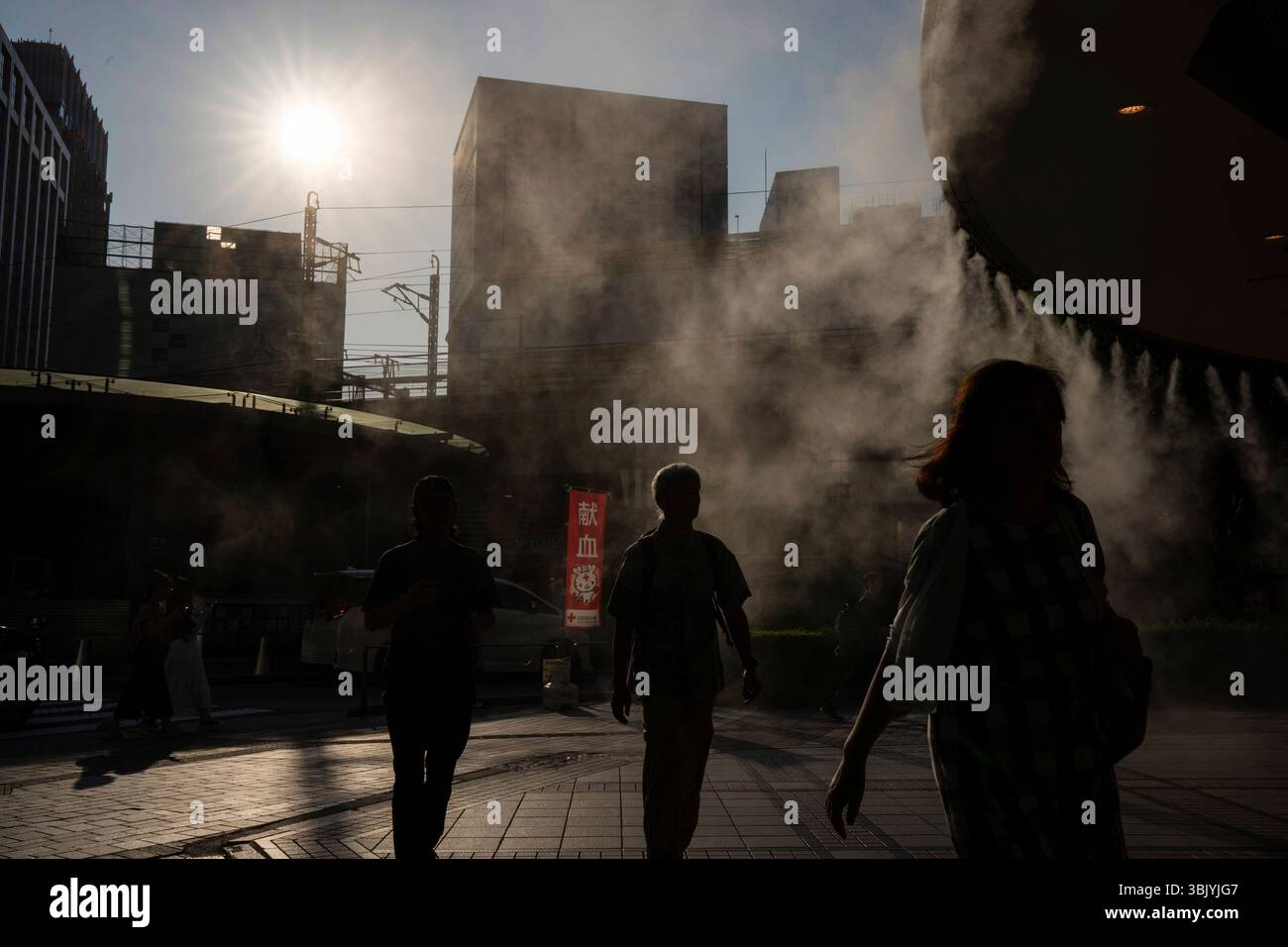 Pedestrians walk through a water mist installation in Tokyo, Tuesday ...