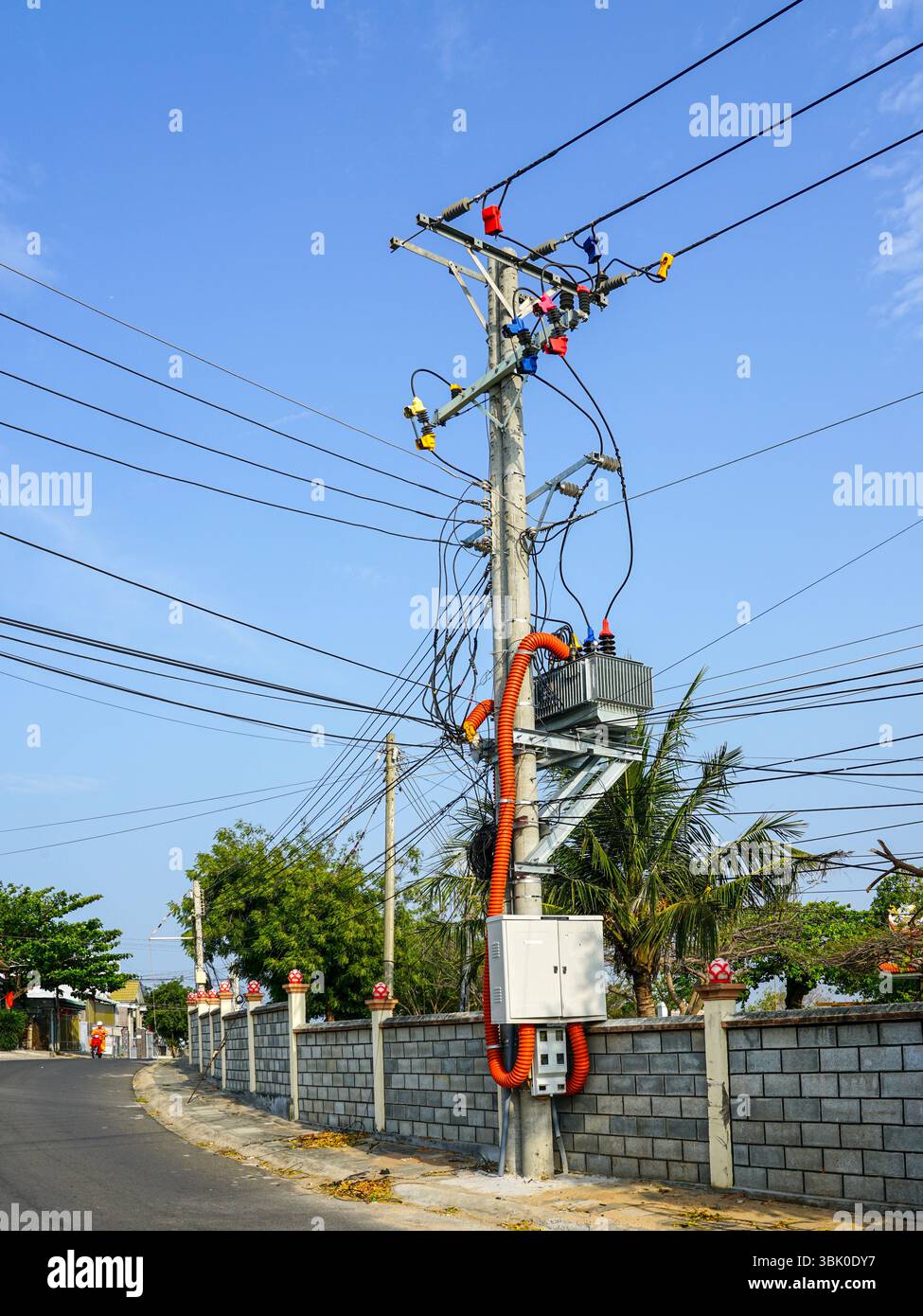 Urban electricity pole with transformer, tangled wires, orange conduit ...