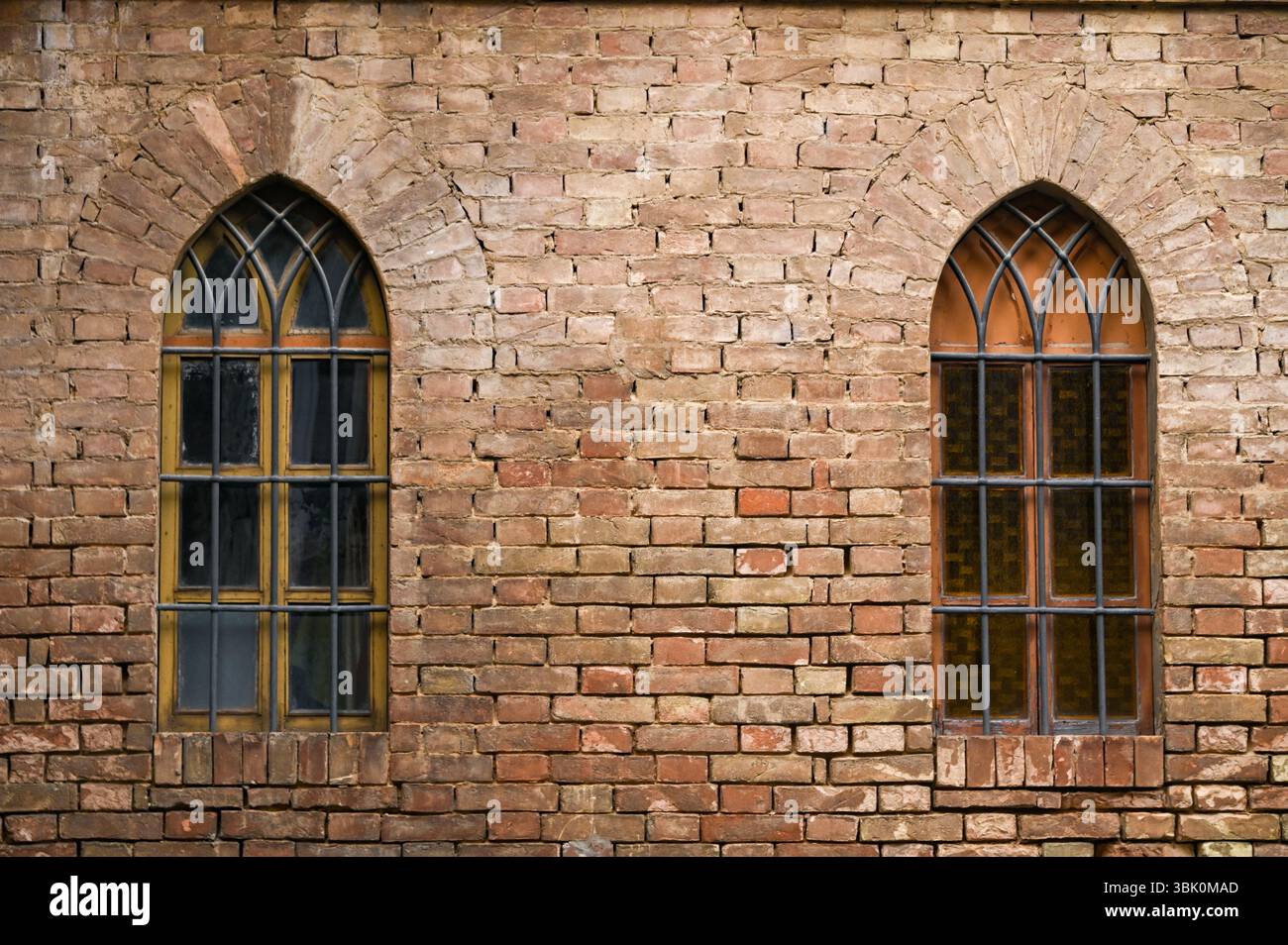 Gothic-style arched windows on an old red brick wall of a historic ...