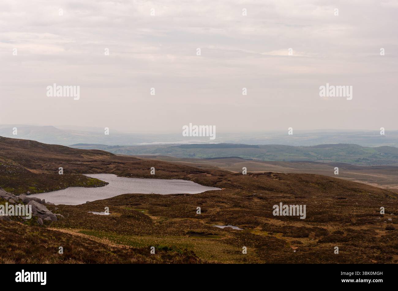 A large, open field with a lake in the middle. The sky is cloudy and ...